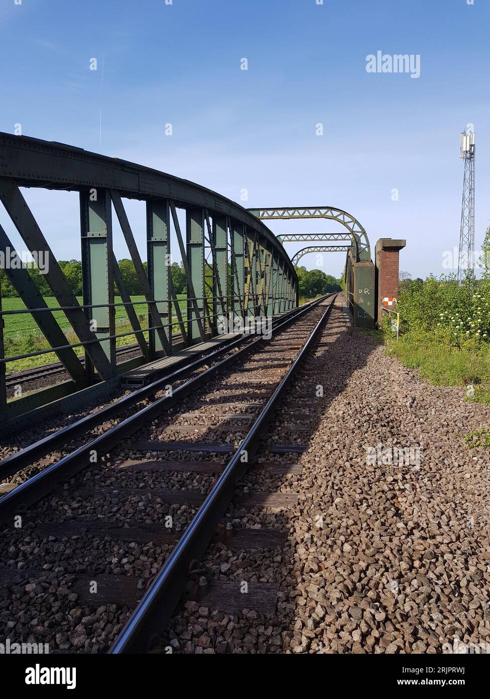 A vintage train bridge spanning a railway track in a rural environment ...