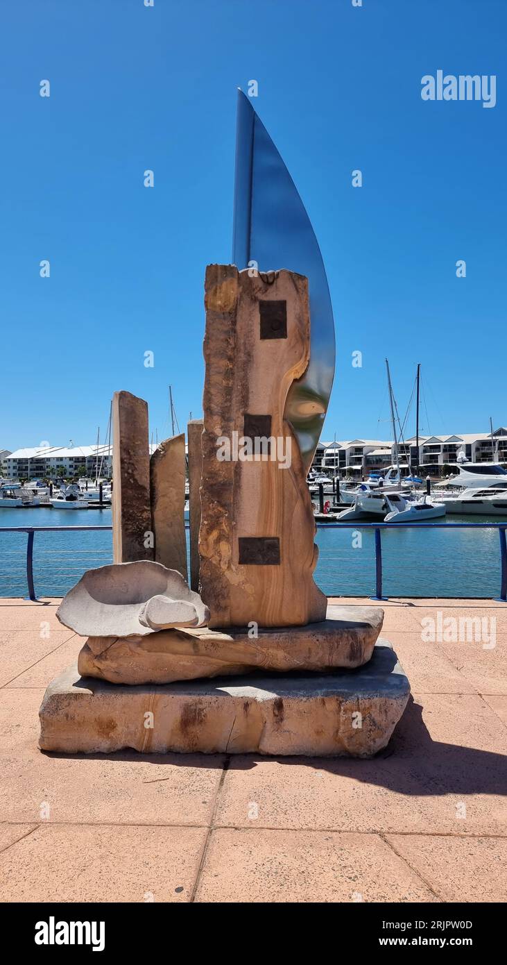 A stunning sculpture stands in the foreground of a bustling harbor and ...