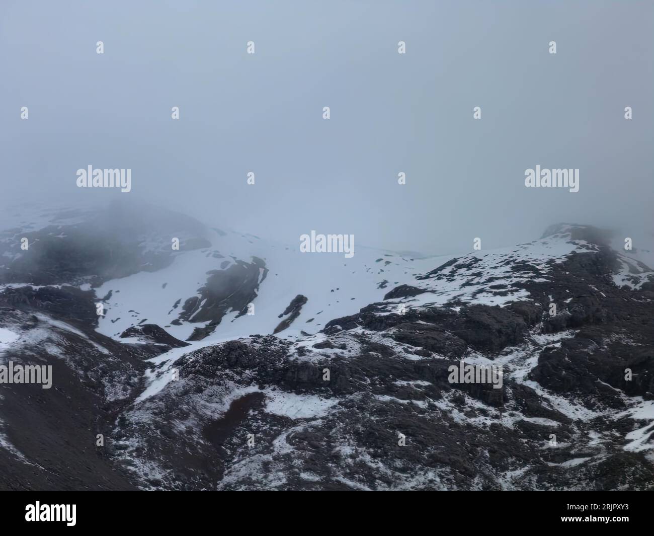 A picturesque view of snow-capped mountains shrouded in misty clouds Stock Photo - Alamy