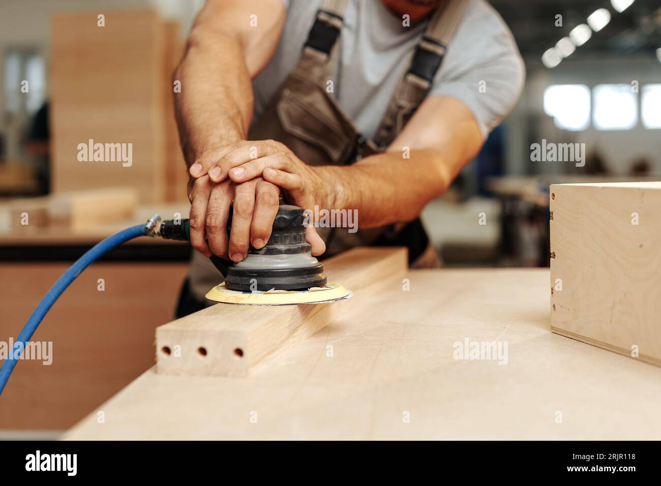 Close up of carpenter hands sanding wood with orbital sander at ...