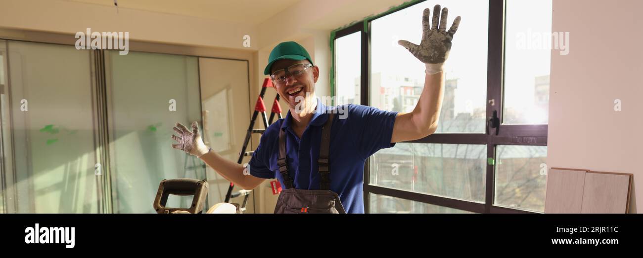 Happy worker in glasses and gloves standing near circular saw and ...