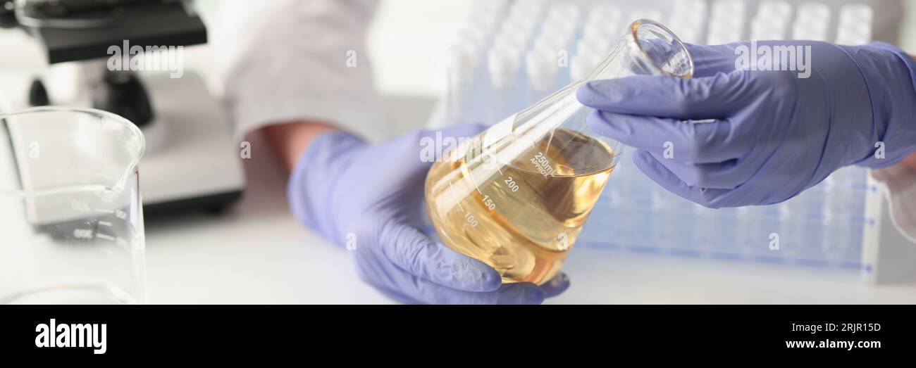 Scientist measuring yellow liquid in flask at chemical laboratory Stock ...