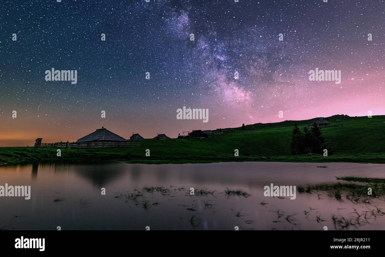 A night sky illuminated by a multitude of stars, with a tranquil lake ...