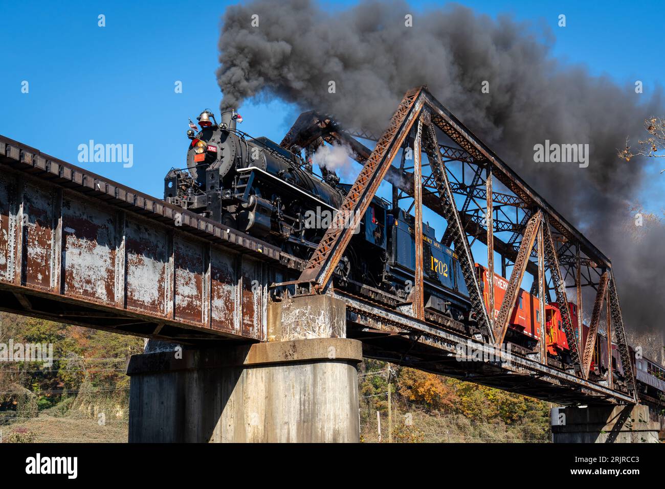 A vintage train chugging across a bridge over a scenic landscape in ...