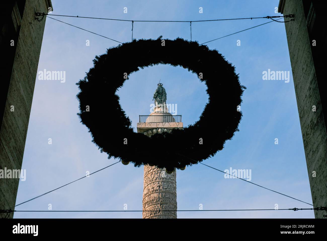 A tall clock tower stands amongst a collection of city buildings, its ...