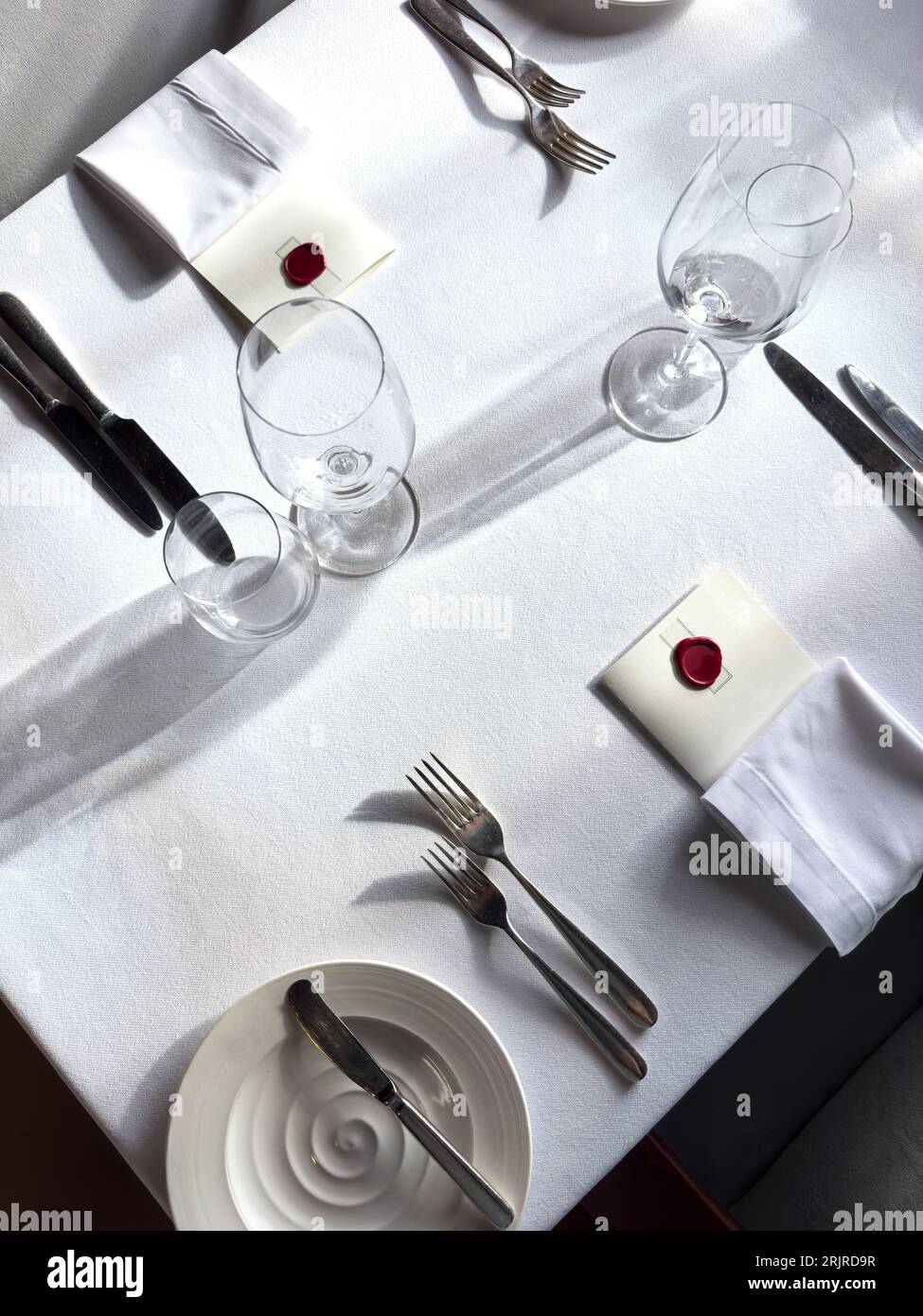 Fine dining table setting with white linen, cutlery, glassware, napkins ...