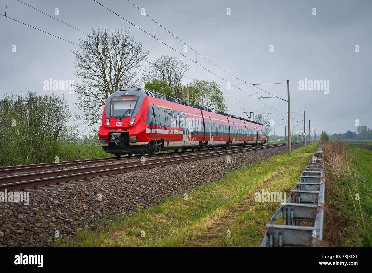 A passenger train chugging along the tracks in a rural setting with ...
