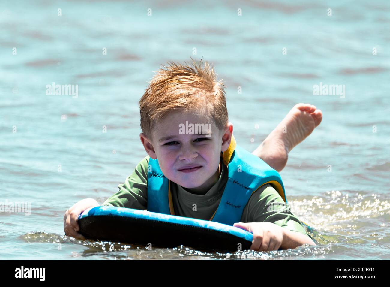 A portrait of a handsome young boy on a bodyboard playing in the waves ...