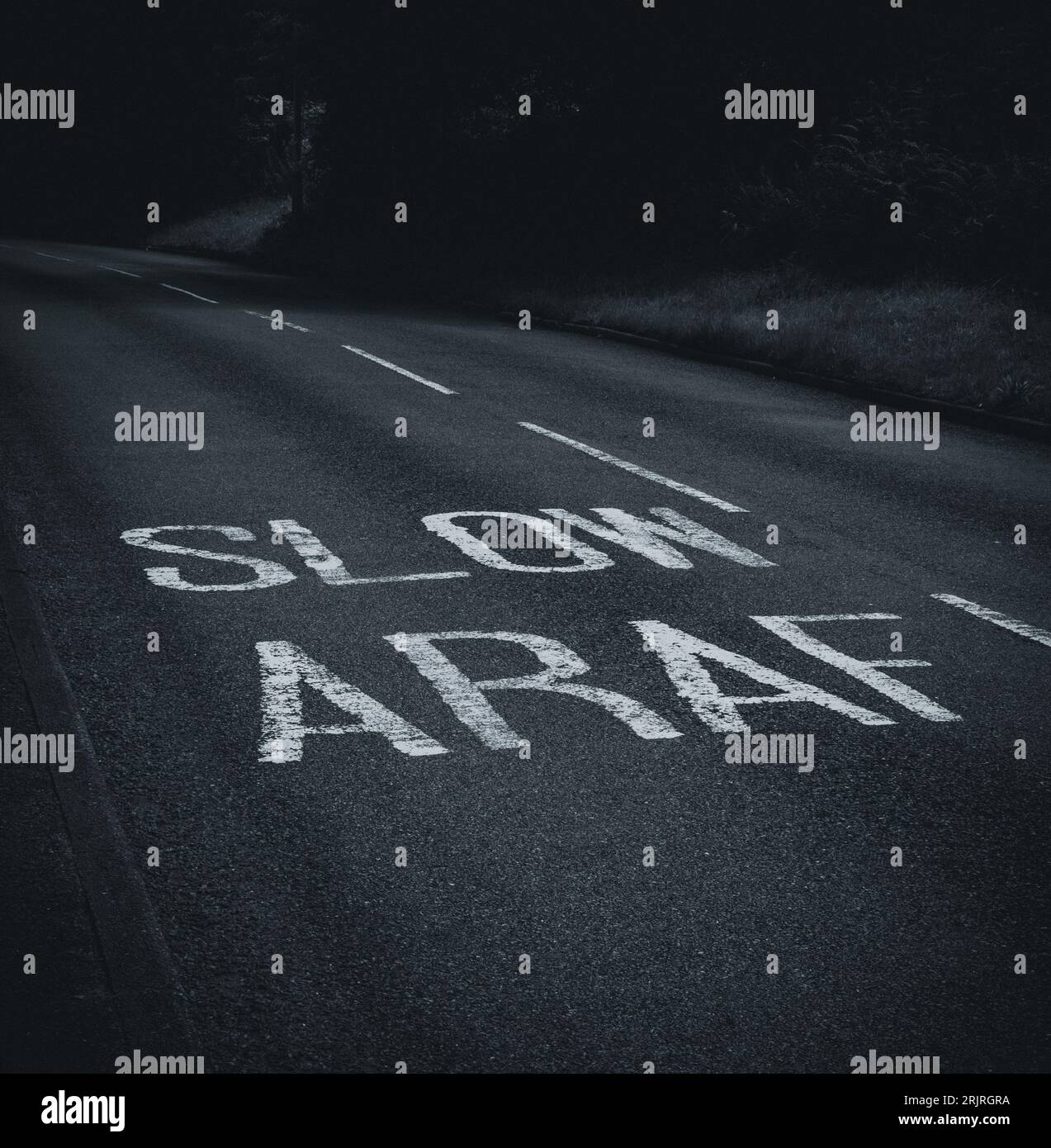 A bilingual slow road marking in Welsh and English Stock Photo - Alamy