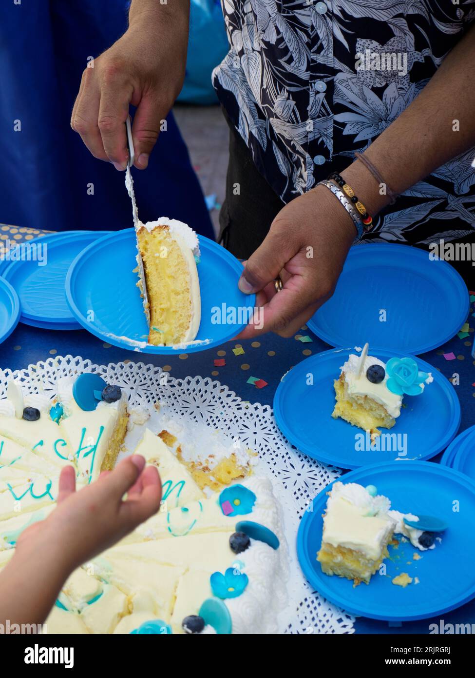 A vertical closeup of people cutting a birthday cake at a party Stock ...