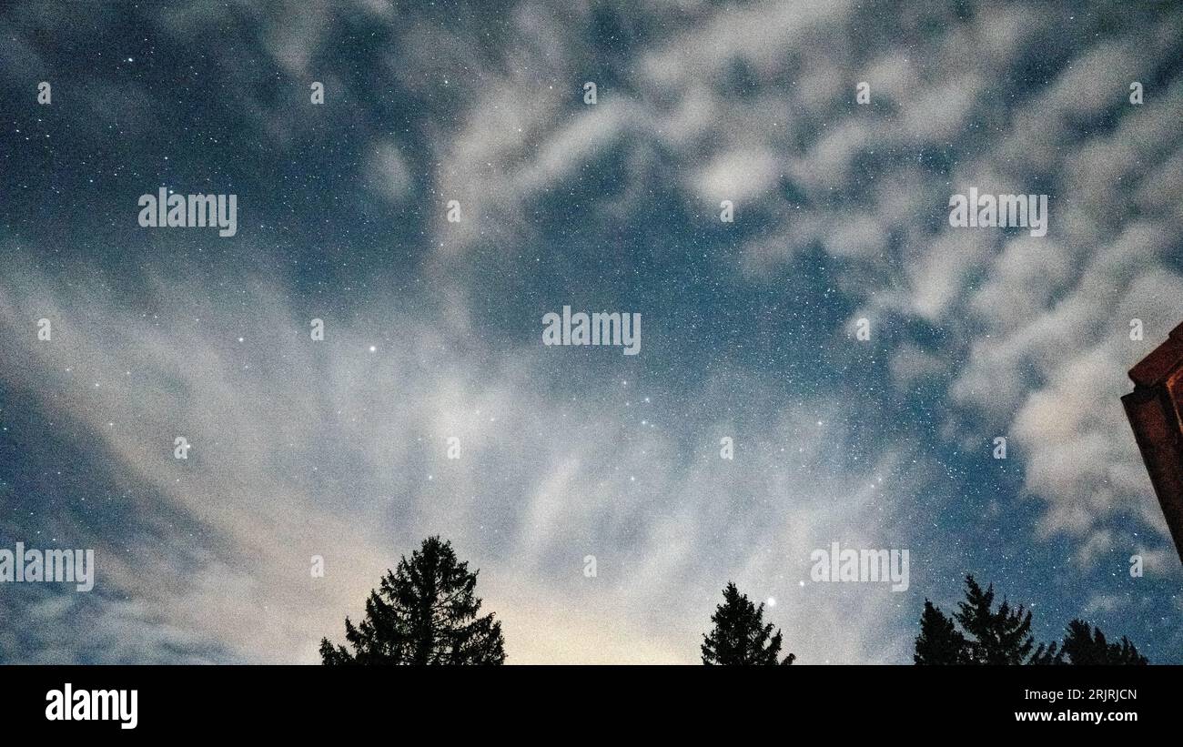 A night sky filled with an array of fluffy clouds illuminated by ...