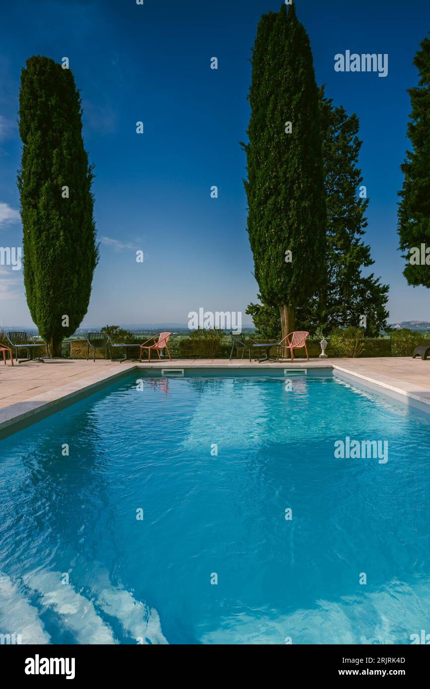 a sun-drenched swimming pool surrounded by lush greenery and empty ...