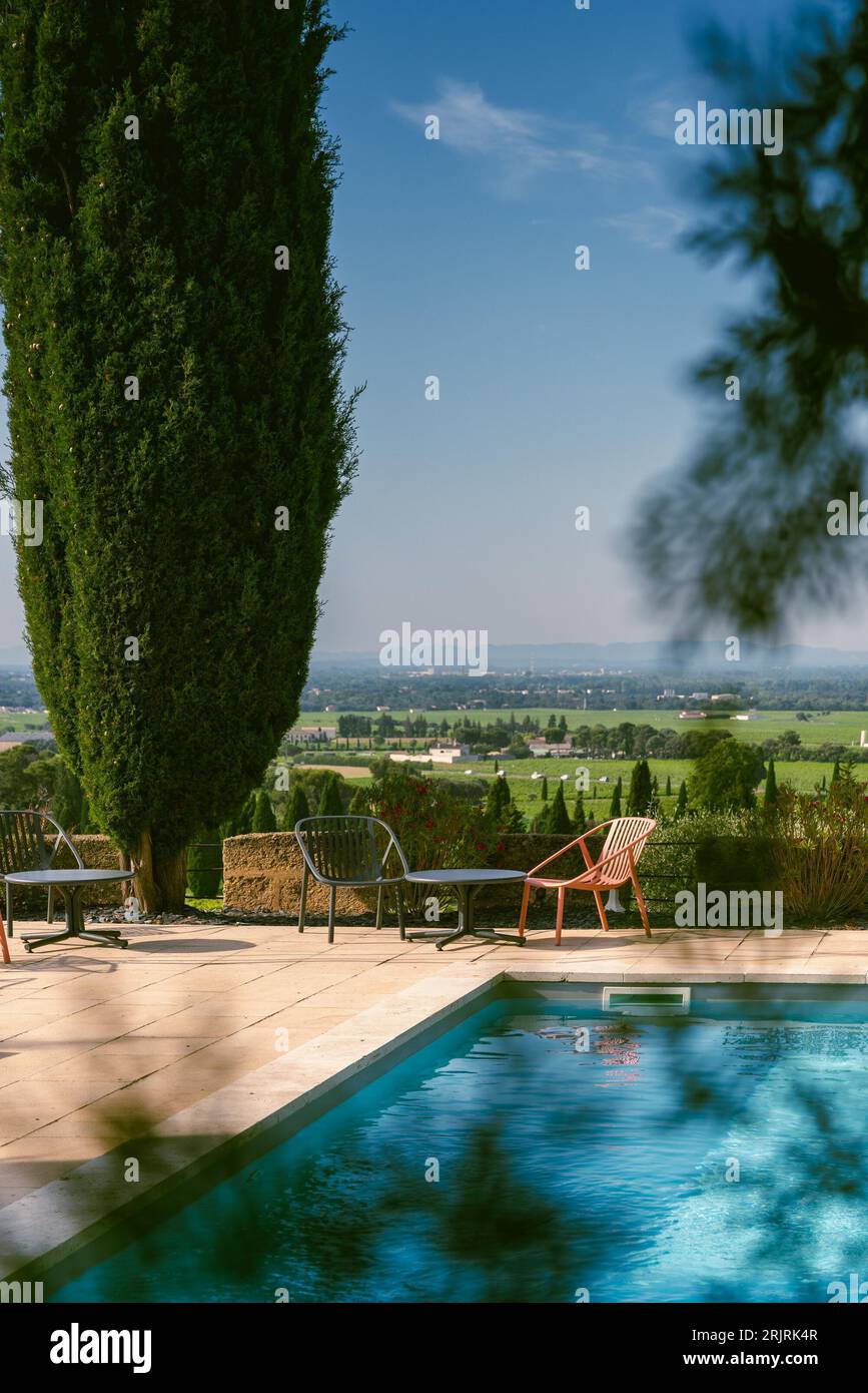 a sun-drenched swimming pool surrounded by lush greenery and empty ...