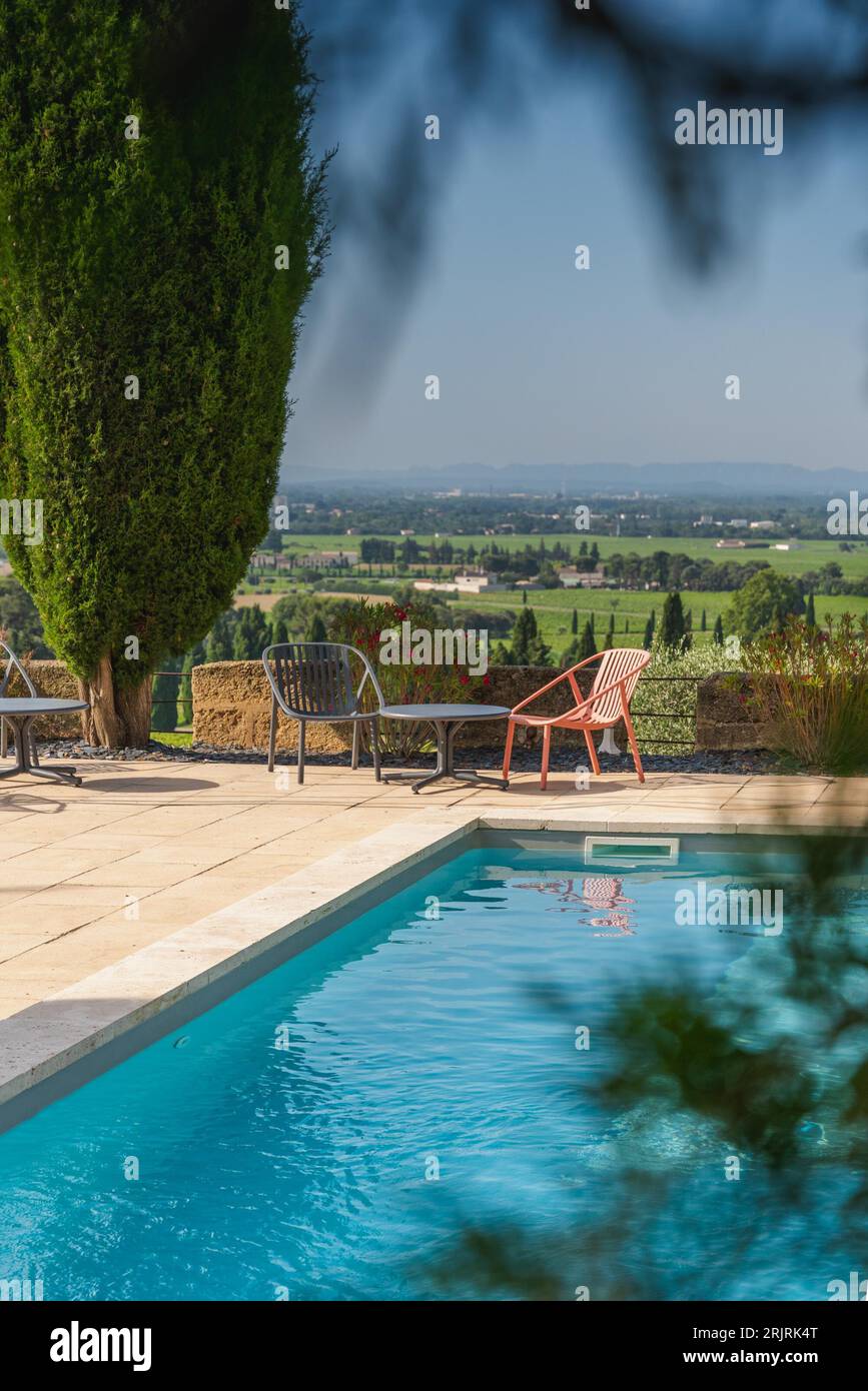 a sun-drenched swimming pool surrounded by lush greenery and empty ...