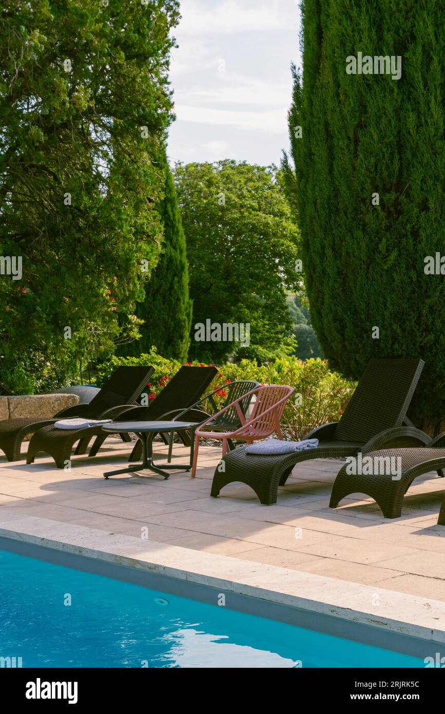 a sun-drenched swimming pool surrounded by lush greenery and empty ...