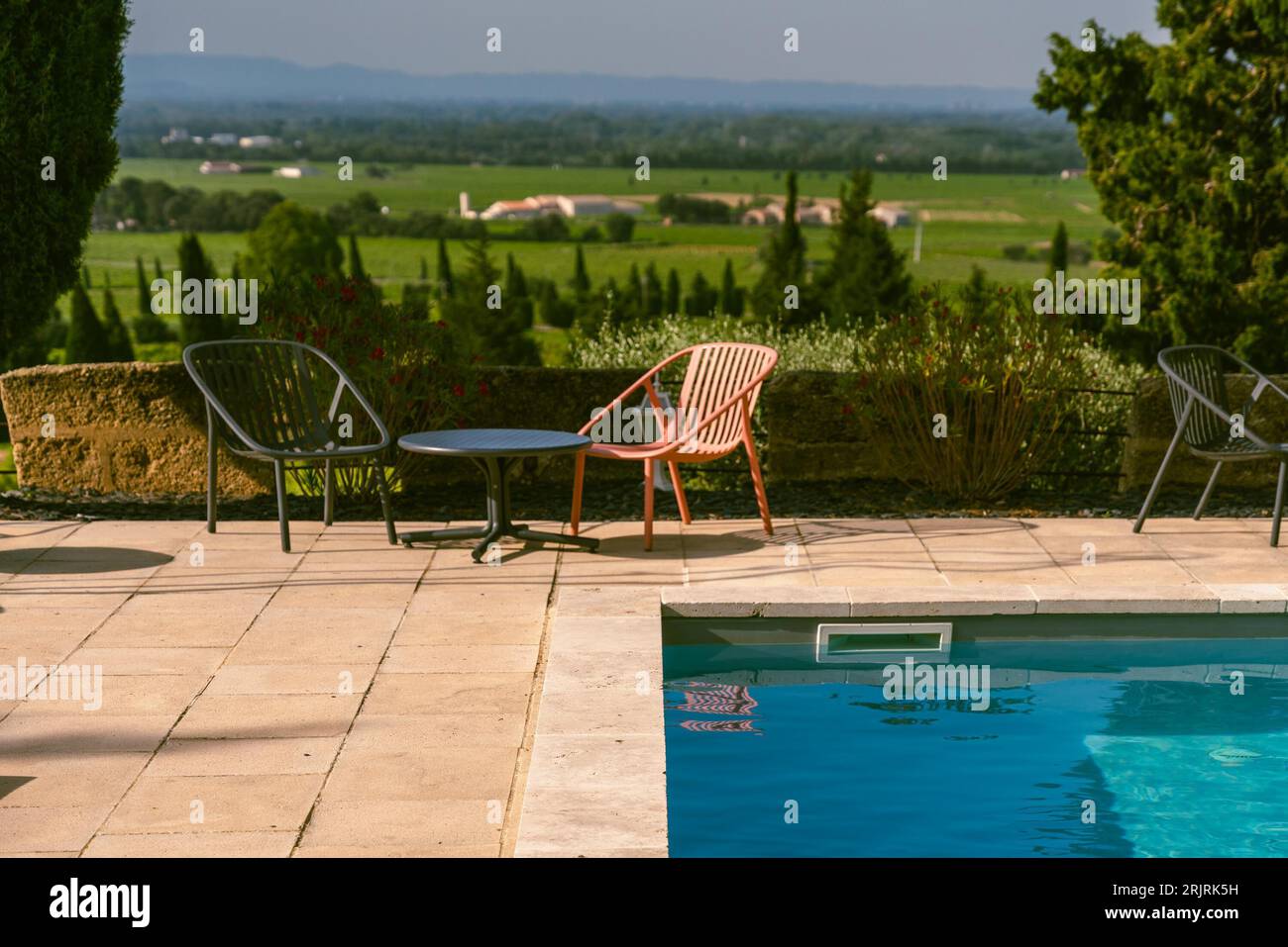 a sun-drenched swimming pool surrounded by lush greenery and empty ...