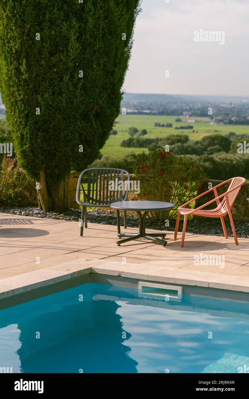 a sun-drenched swimming pool surrounded by lush greenery and empty ...