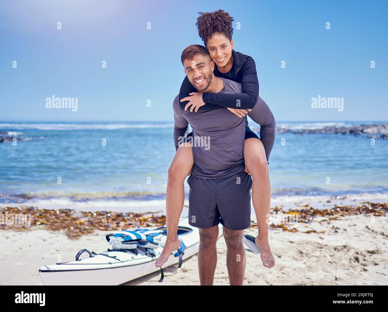 Sports, fitness and kayak couple piggyback at a beach for training ...