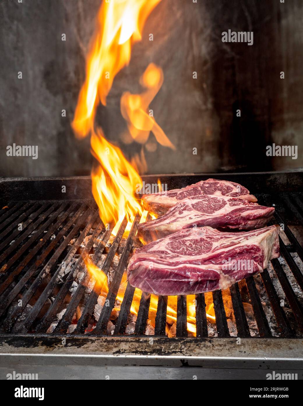 A closeup of two steaks cooking on a charcoal grill Stock Photo - Alamy