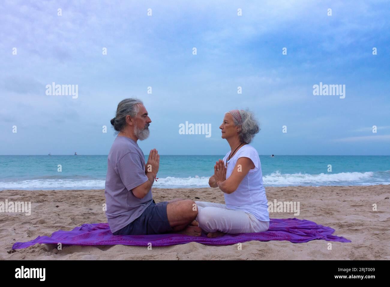 Couple meditating together in a prayer sitting position favoring the ...