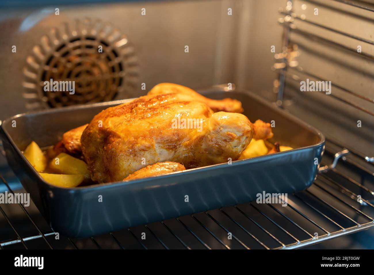 A roasting pan containing a whole chicken inside an oven Stock Photo ...