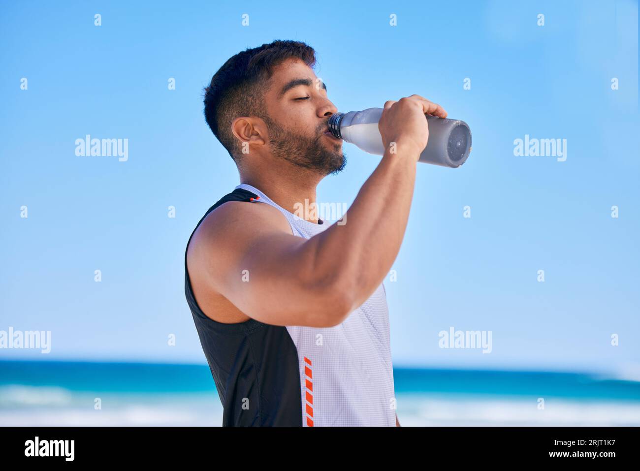 Man, fitness and drinking water on beach in hydration after workout ...