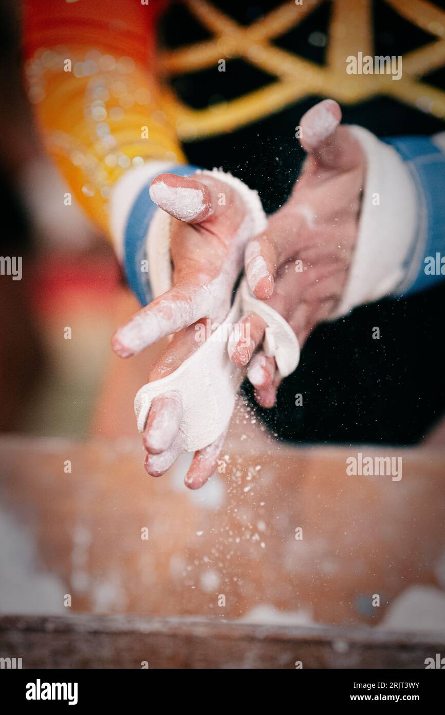 An image of a gymnast dusting their hands with chalk before a ...