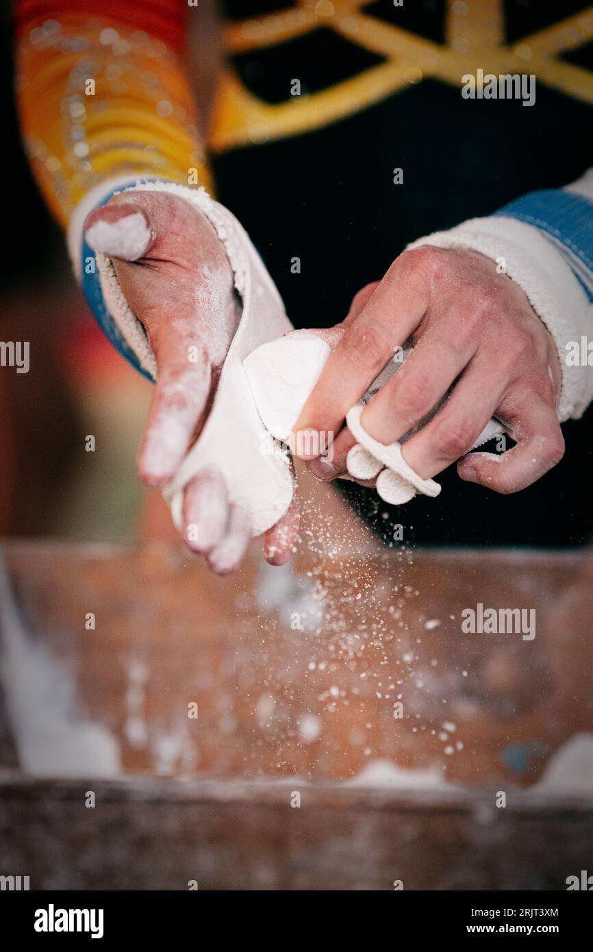 An image of a gymnast dusting their hands with chalk before a ...