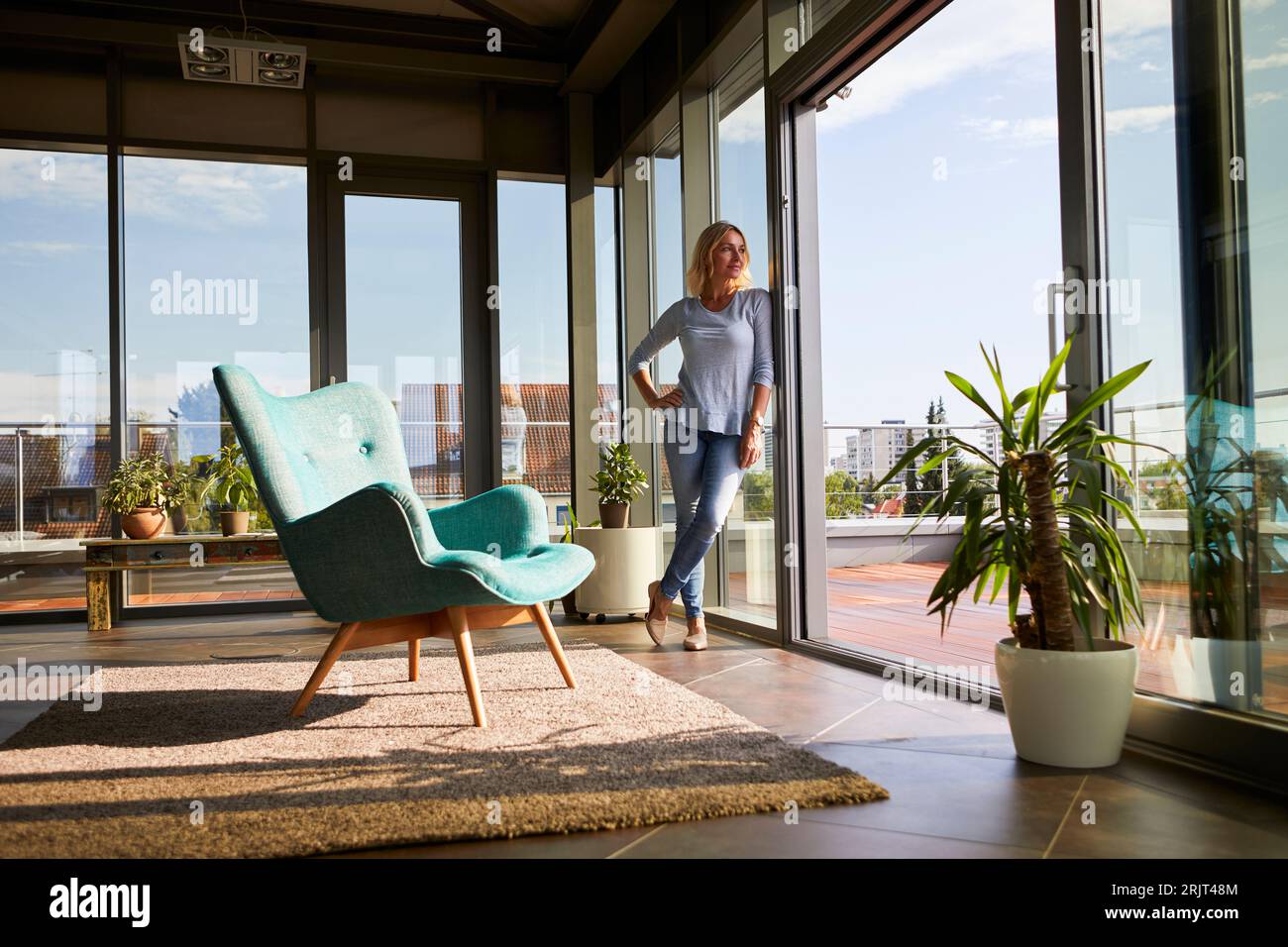 Mature woman standing at the window at home looking out Stock Photo - Alamy