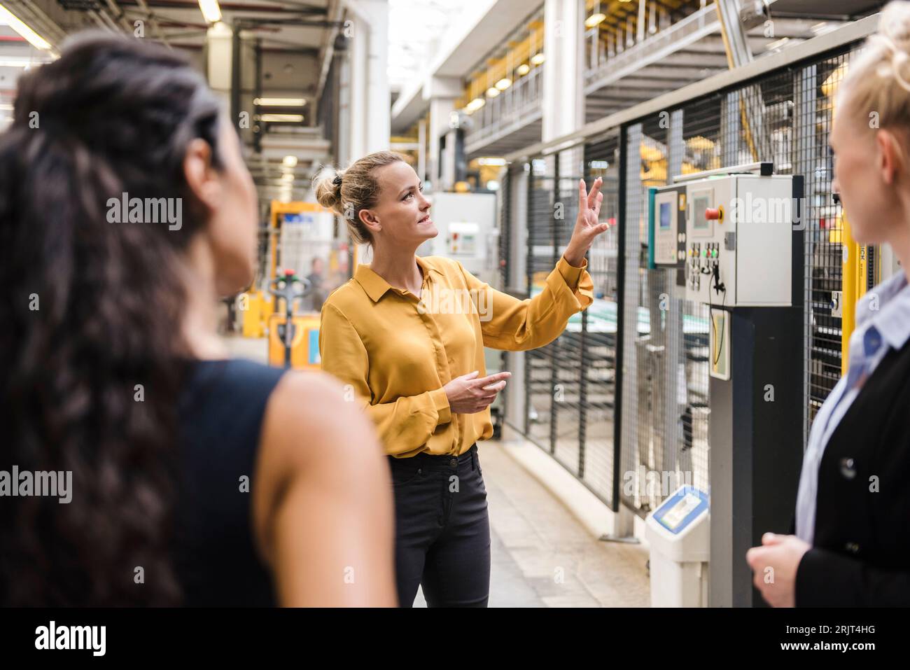 Woman explaining machine to colleagues in modern factory Stock Photo ...