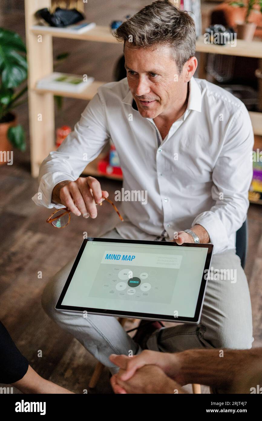 Businessman explaining a mind map on tablet screen during a ...