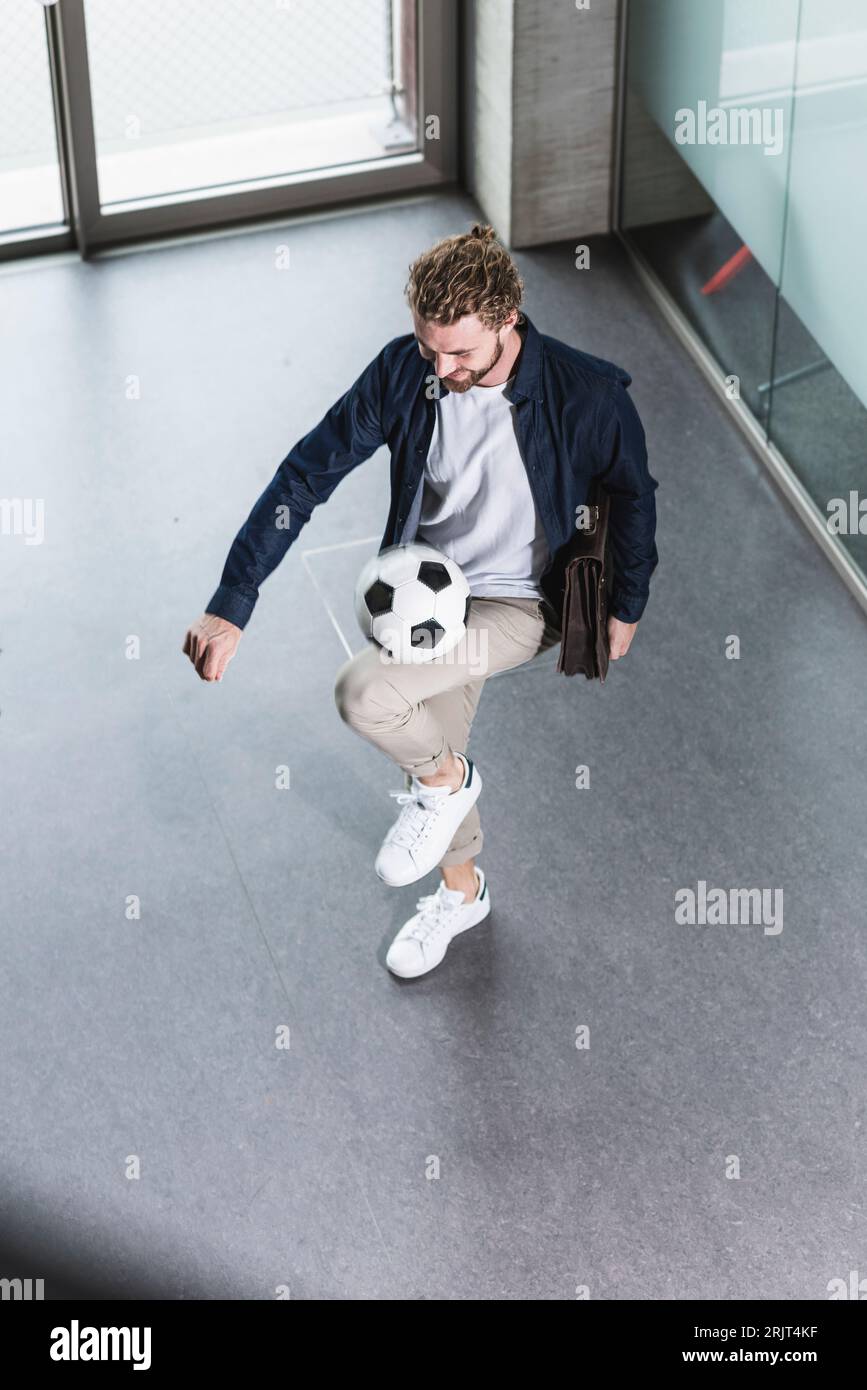 Businessman playing football in office hi-res stock photography and ...