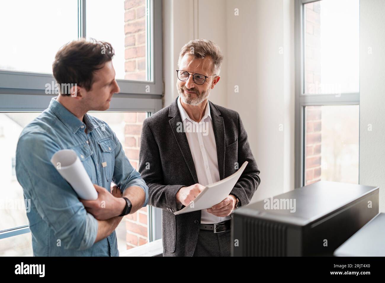 Two colleagues talking at the window in office Stock Photo - Alamy