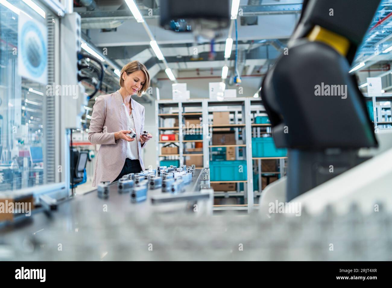 Businesswoman examining workpieces in a modern factory hall Stock Photo ...