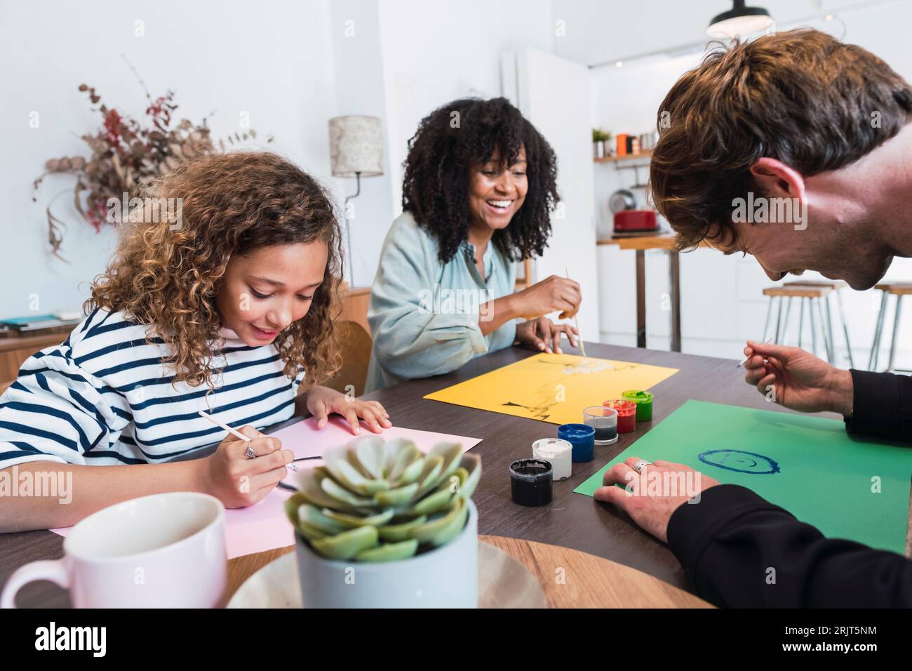 Family sitting at table drawing and painting together Stock Photo - Alamy
