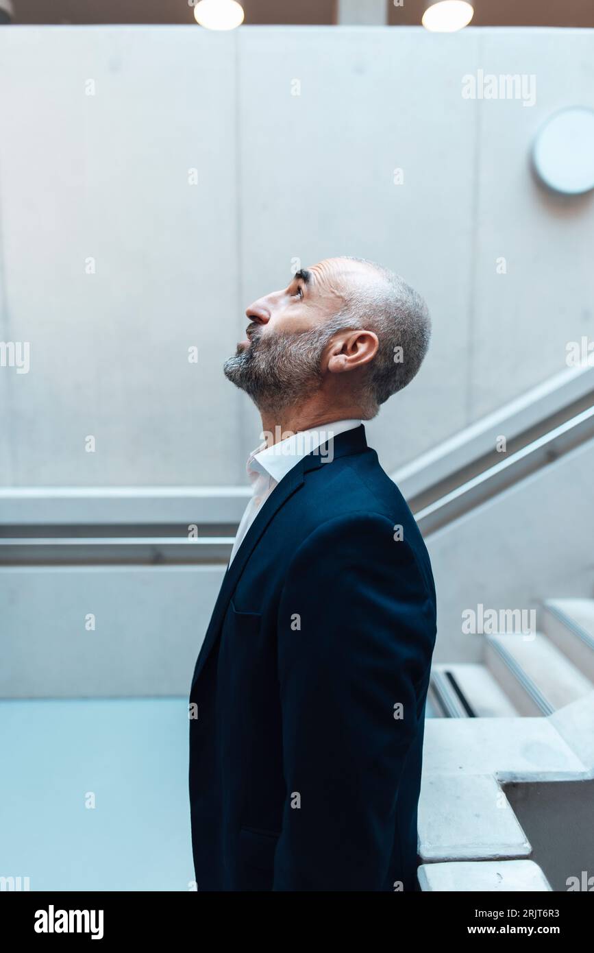 Businessman standing and looking up Stock Photo - Alamy