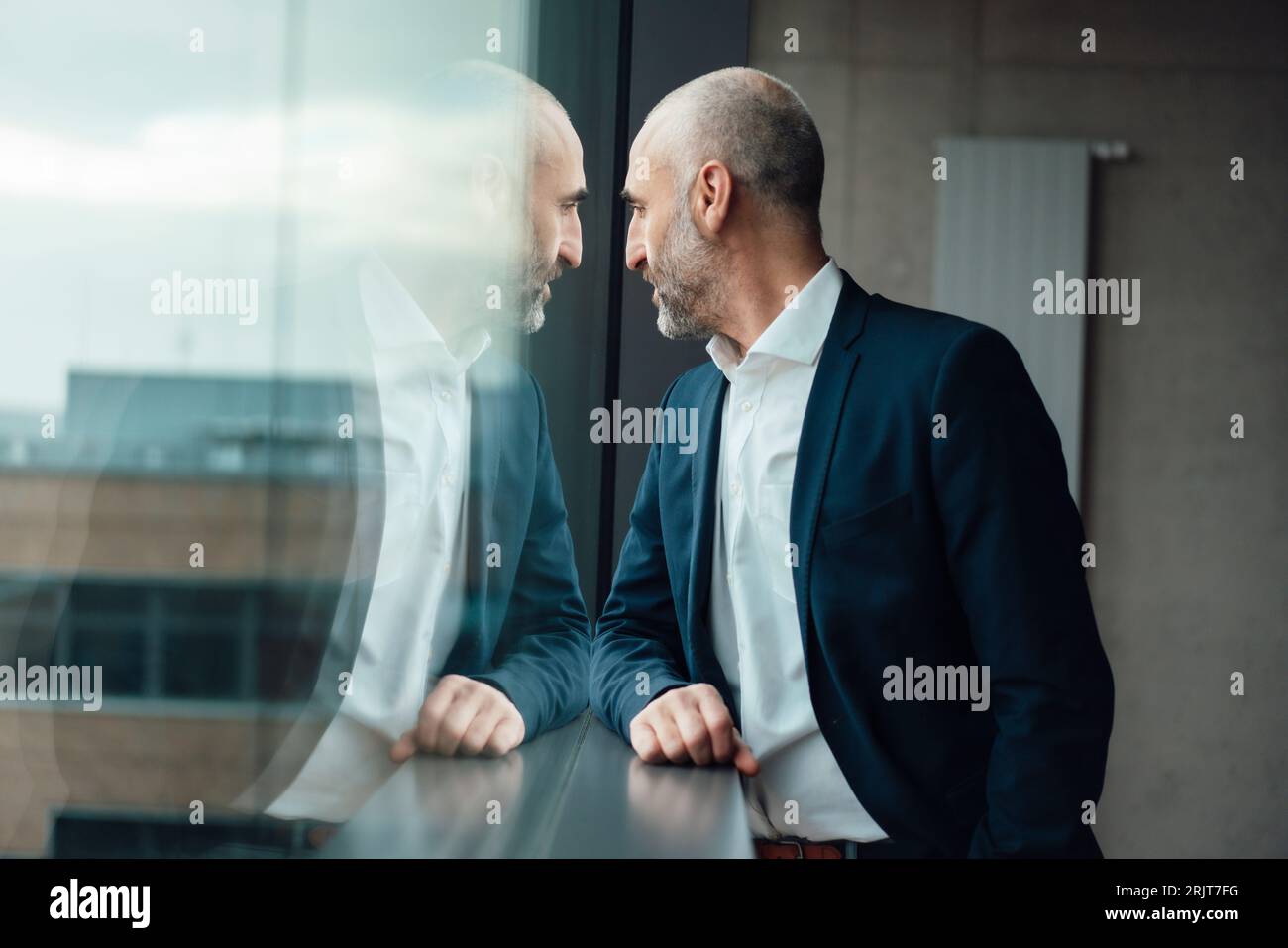 Mature businessman looking through glass window Stock Photo - Alamy