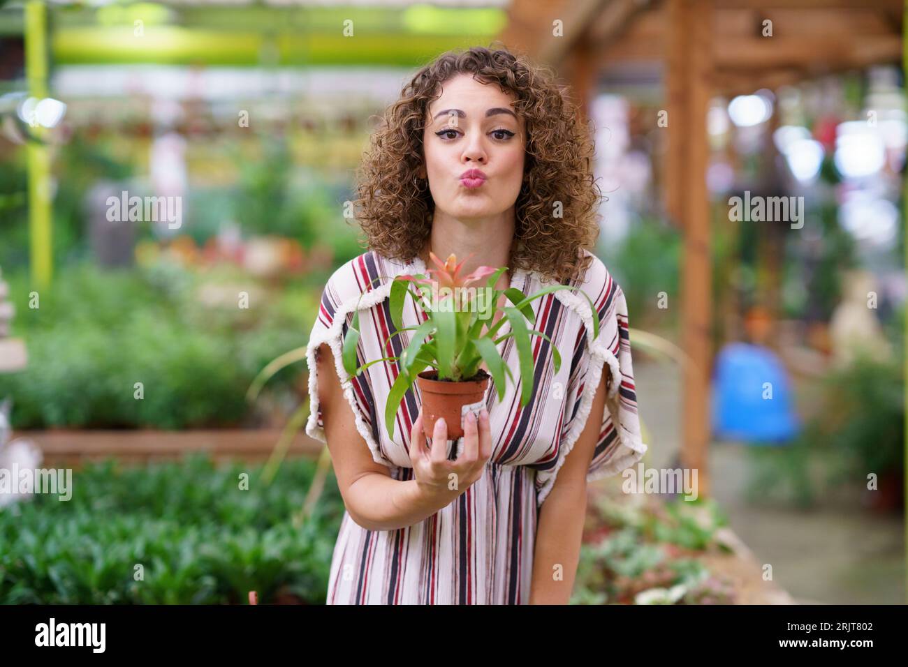 Woman puckering lips holding plant standing at nursery Stock Photo - Alamy