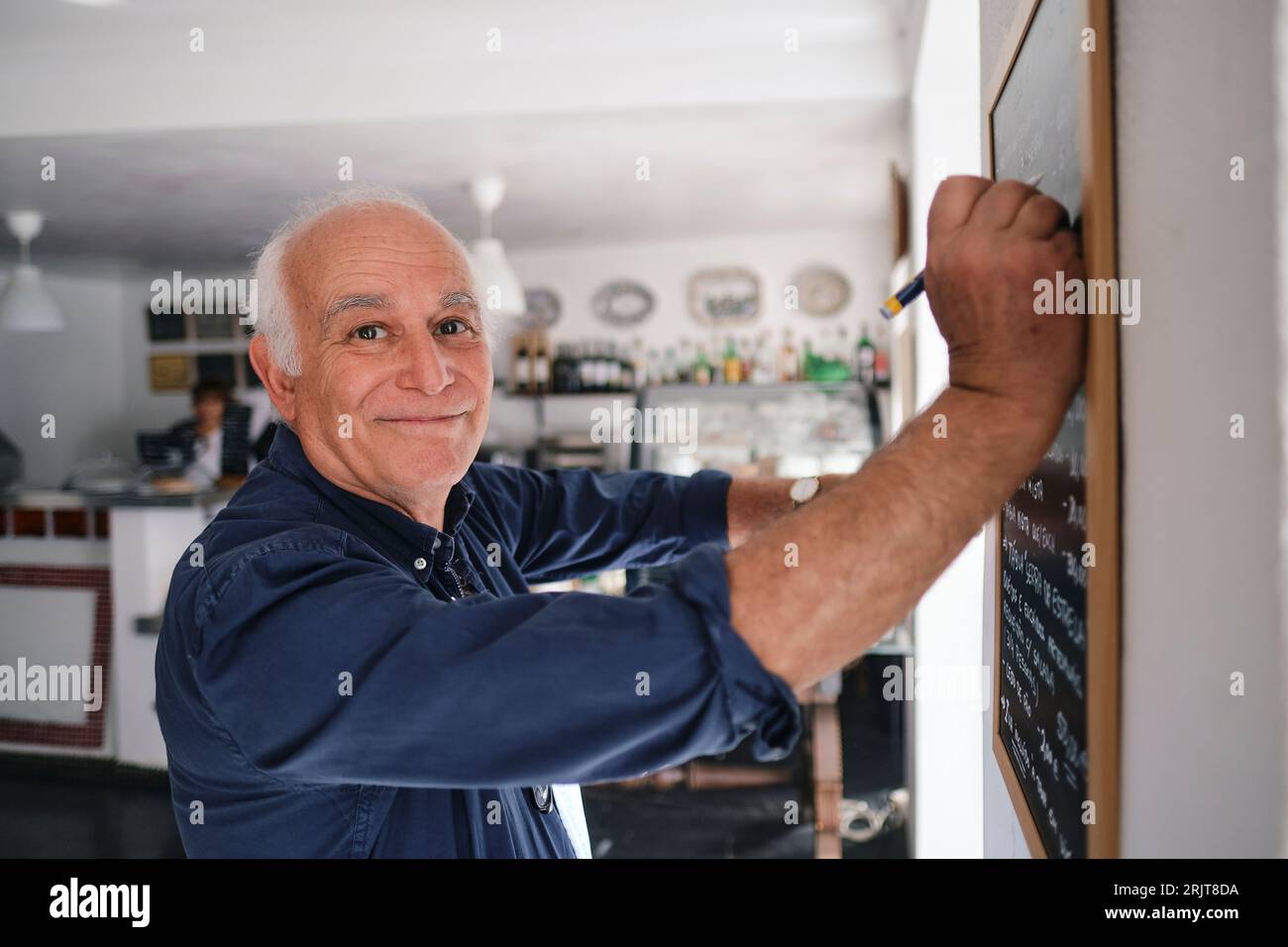 Smiling cafe owner writing on board with pen Stock Photo - Alamy