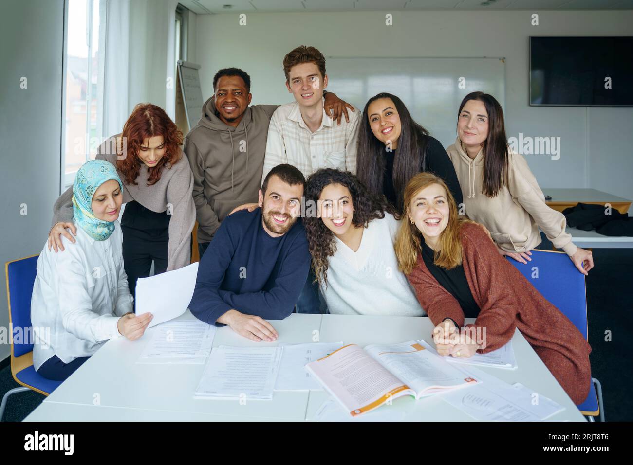 Happy students sitting near table in classroom Stock Photo - Alamy
