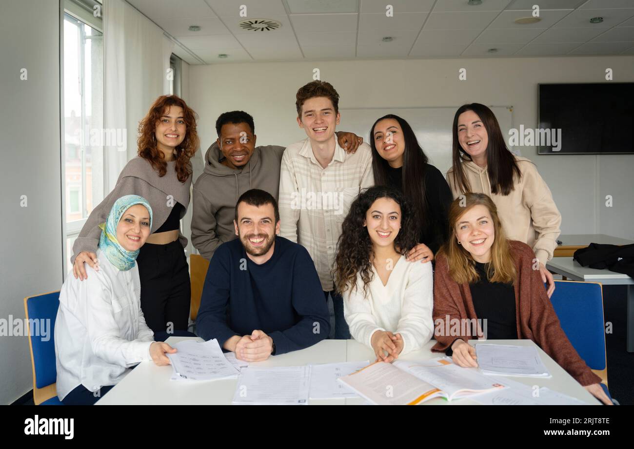 Multi-ethnic students sitting near table with books in classroom Stock ...