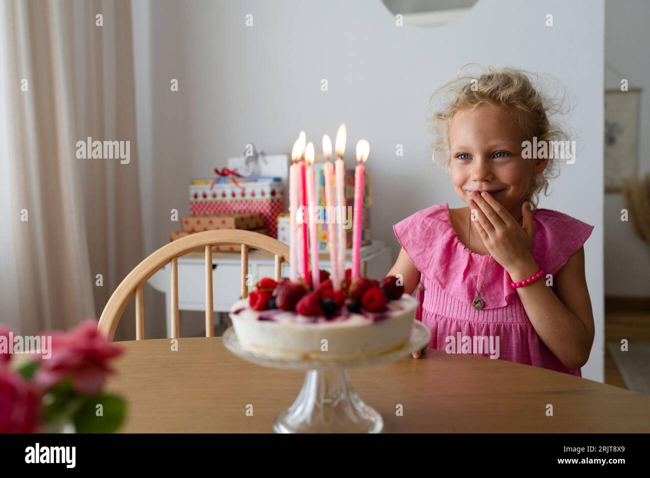 Smiling girl standing behind cake with candles at home Stock Photo - Alamy