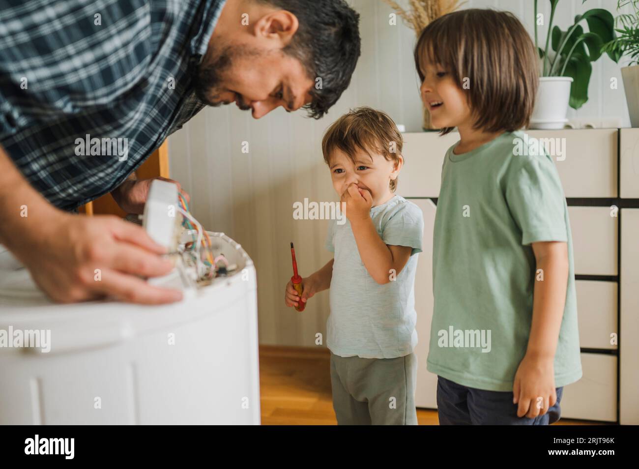 Happy children watching father repairing washing machine at home Stock ...