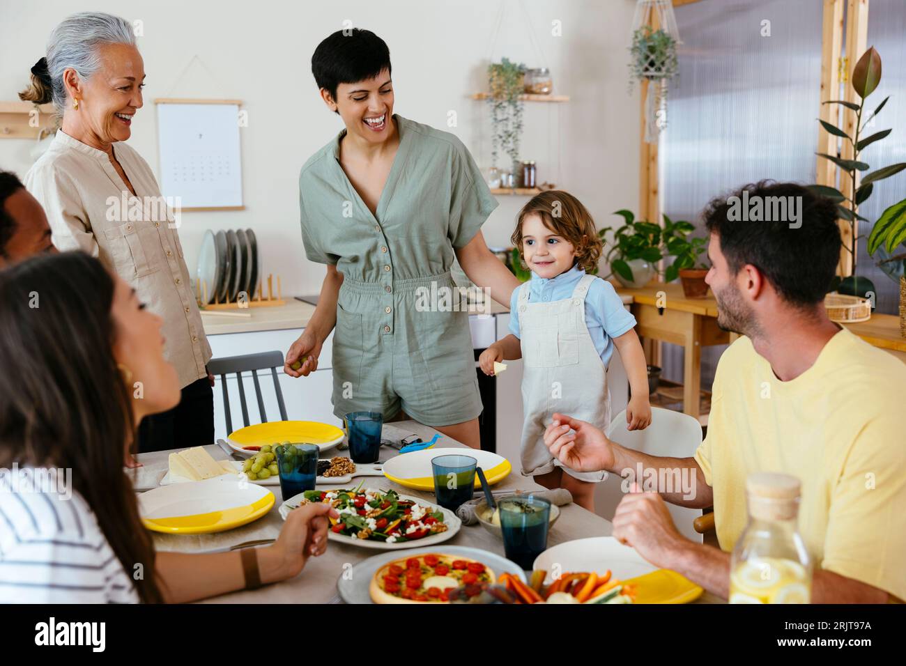 Smiling family talking to boy near dining table at kitchen Stock Photo ...