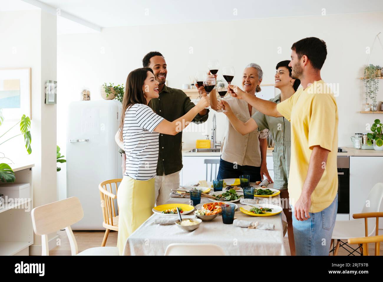 Happy family raising toast standing near dining table in kitchen Stock ...