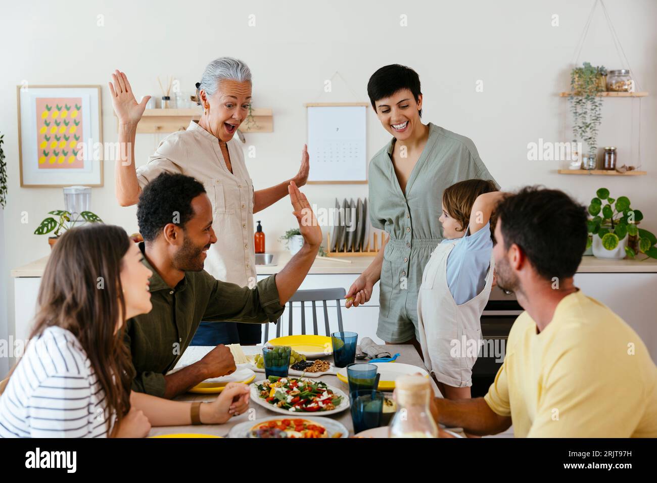 Smiling family giving high-five on dining table in kitchen Stock Photo ...