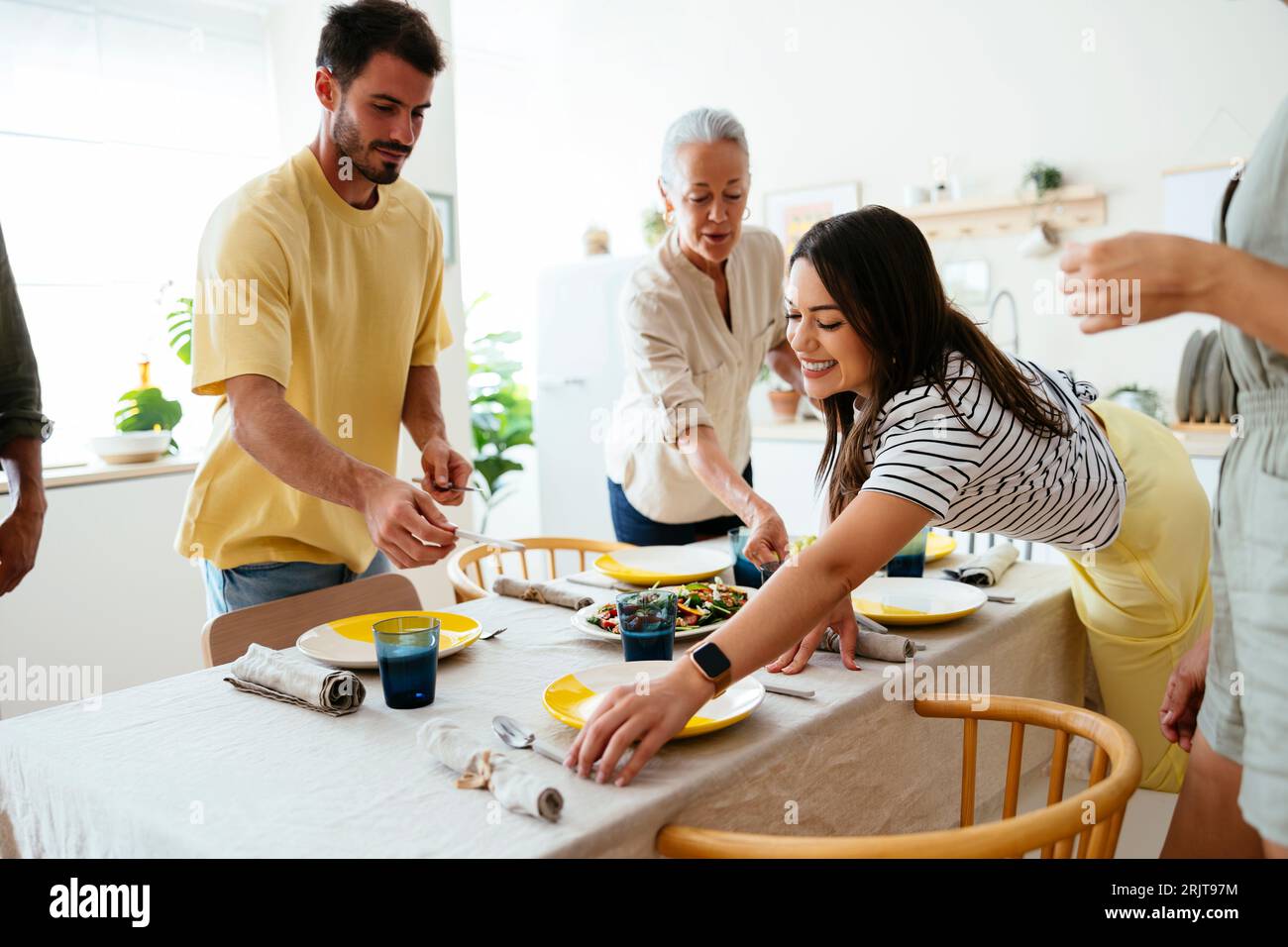 Happy family setting table in kitchen Stock Photo - Alamy