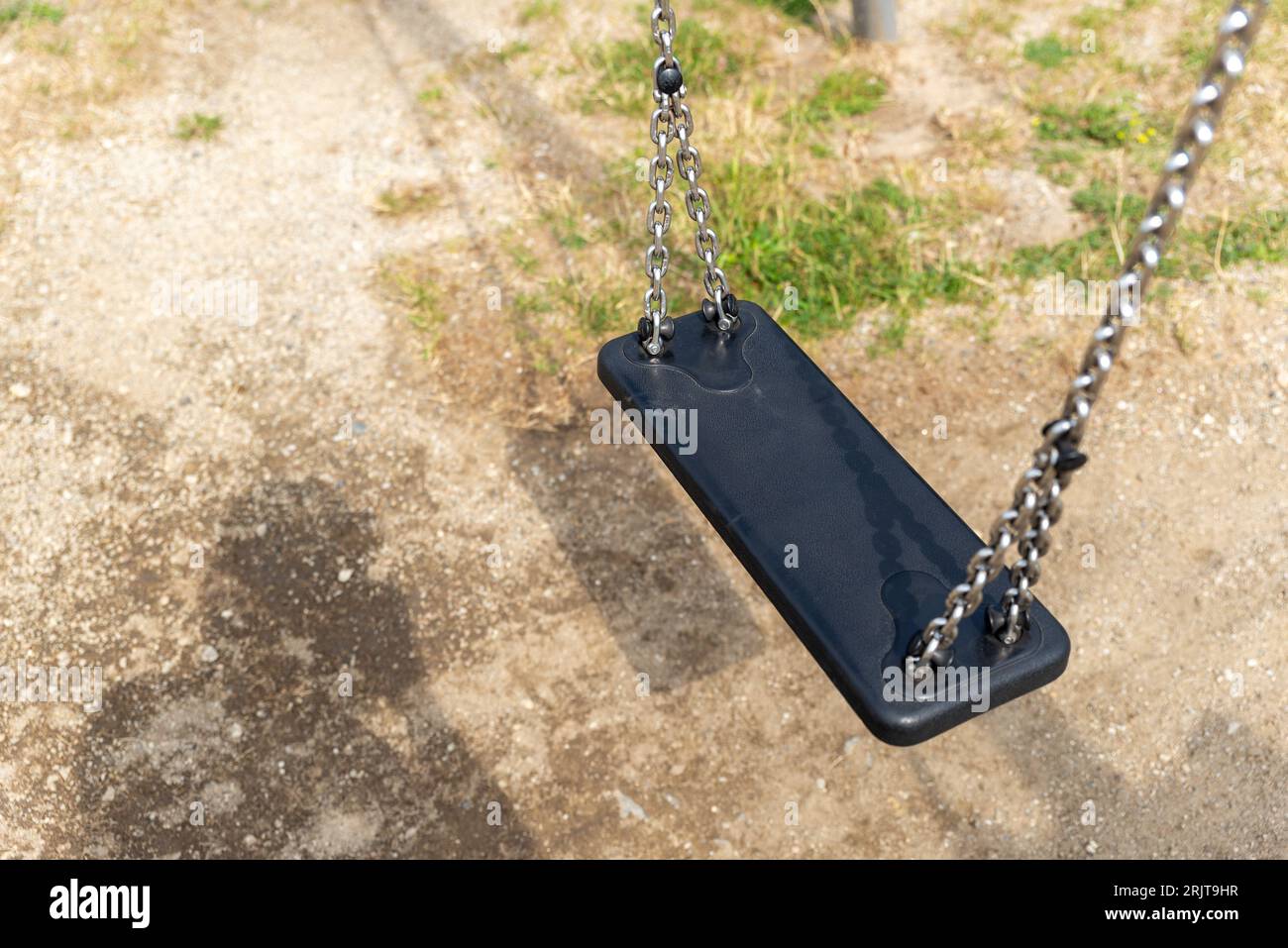 black plastic swing on chains, no backrest, playground Stock Photo - Alamy