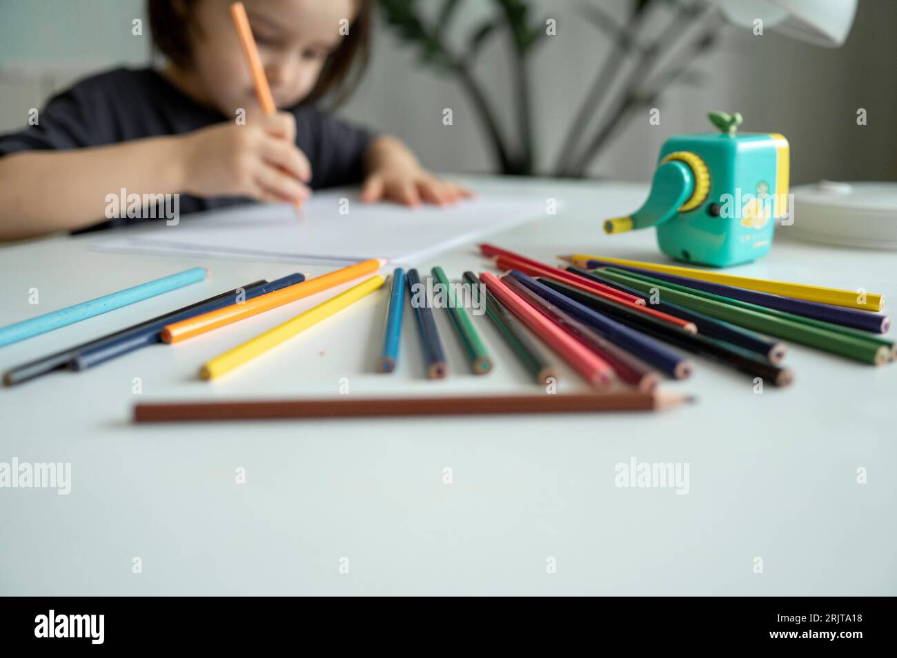 Boy drawing with colored pencils on table at home Stock Photo - Alamy