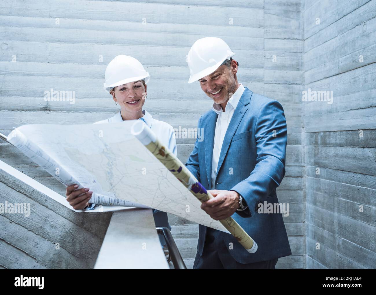 Happy architects working and planning with blueprint at site Stock ...